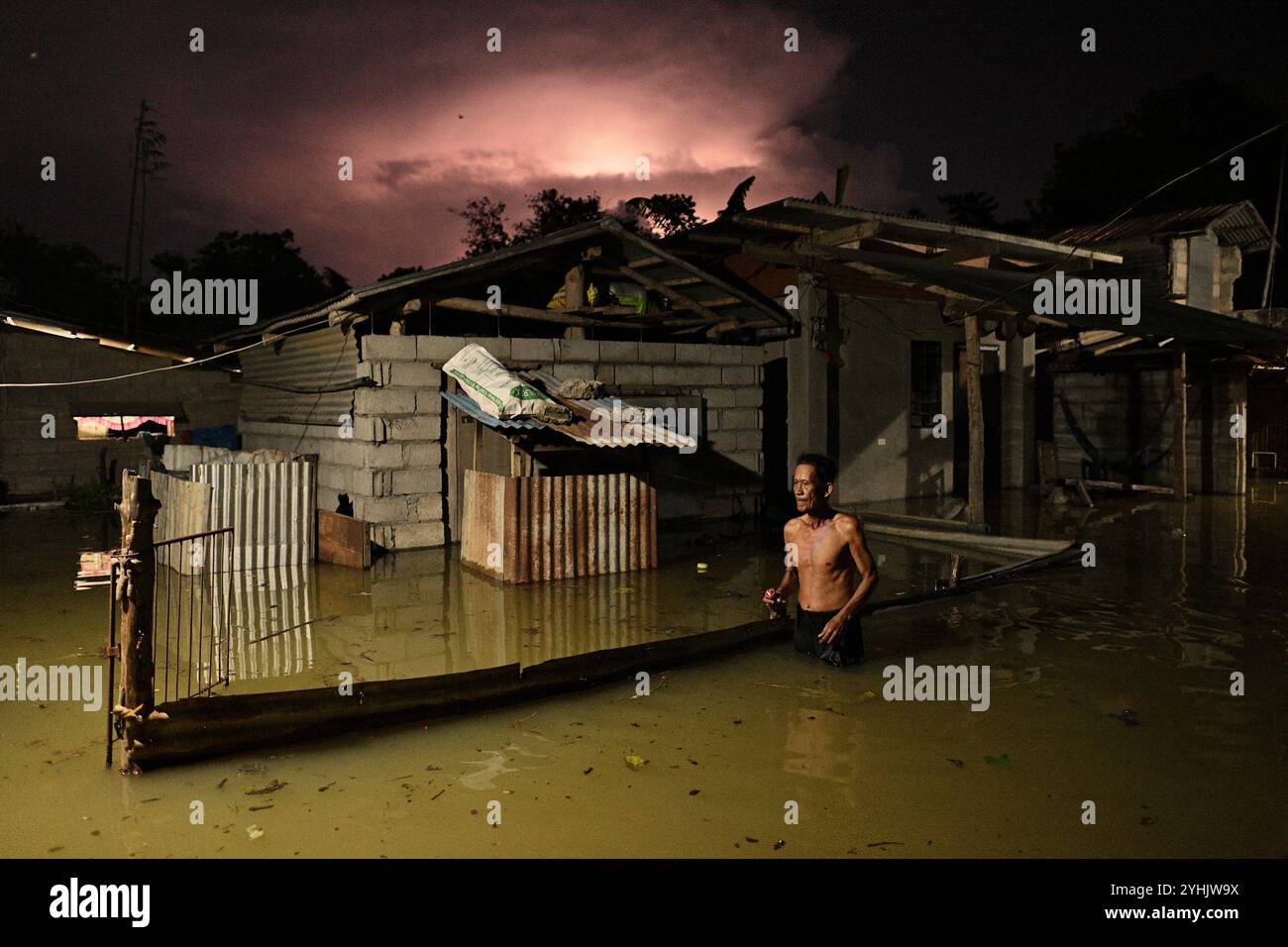 A resident wades through a flooded street caused by heavy rains from ...