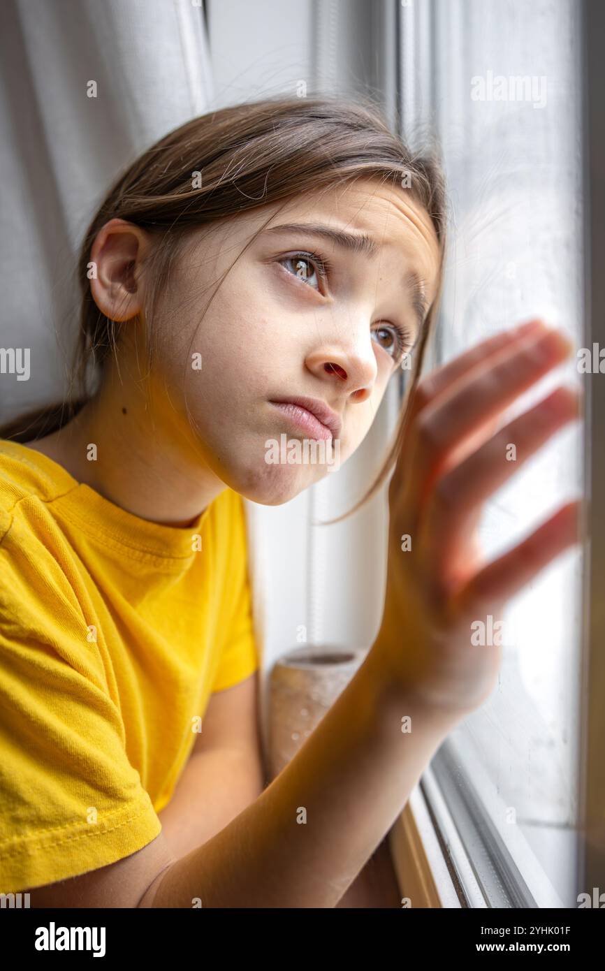 A gloomy and sad girl looks out the window. Emotions concept Stock ...