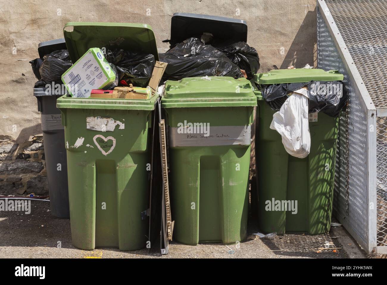 Green and grey plastic recycling and thrash bins filled with cardboard ...
