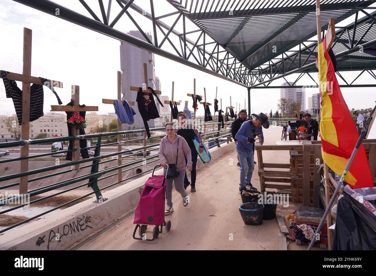 People pass by symbolic crosses on a bridge after floods in Catarroja ...