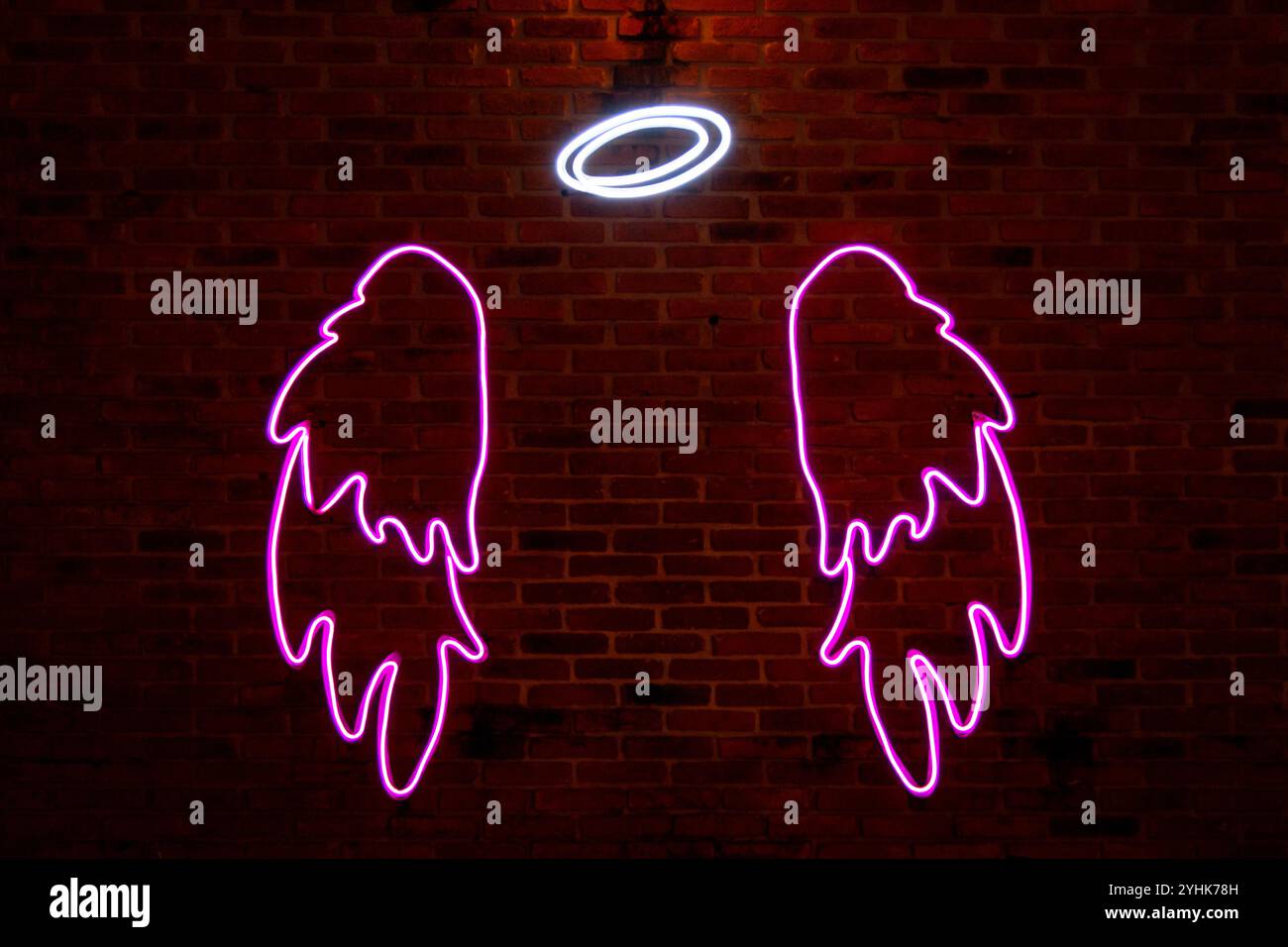 A neon light shaped into one white aureole and two pink angel wings on ...