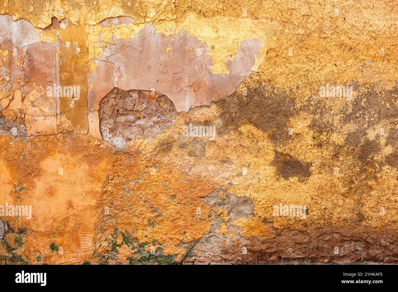 A vibrant yellow wall shows signs of weathering at the base, revealing ...