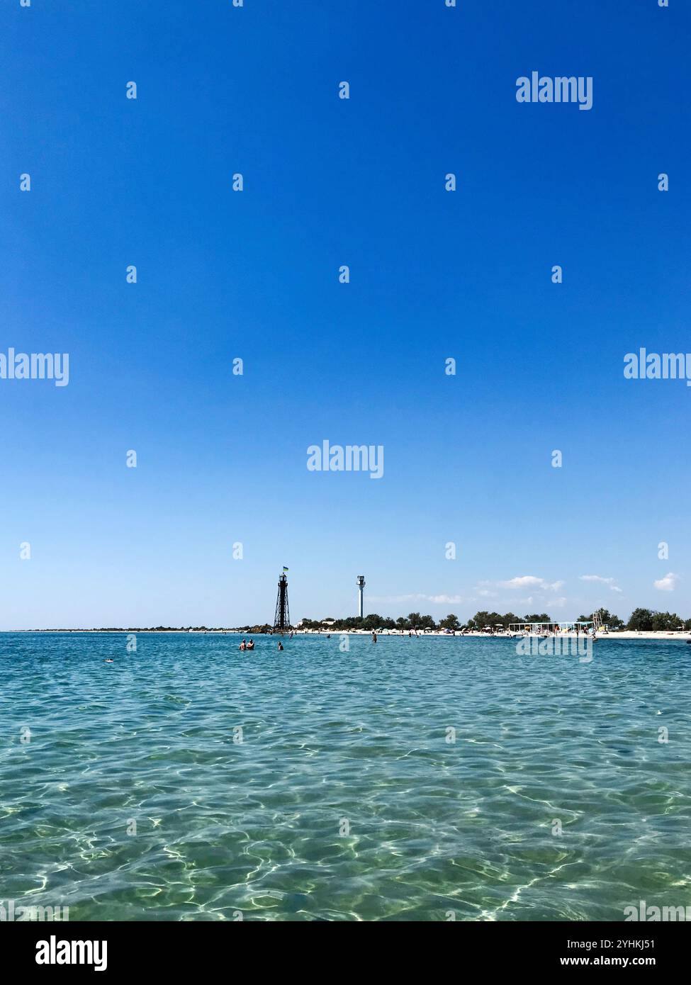 A beautiful clear blue ocean stretches towards a distant beach, under a ...