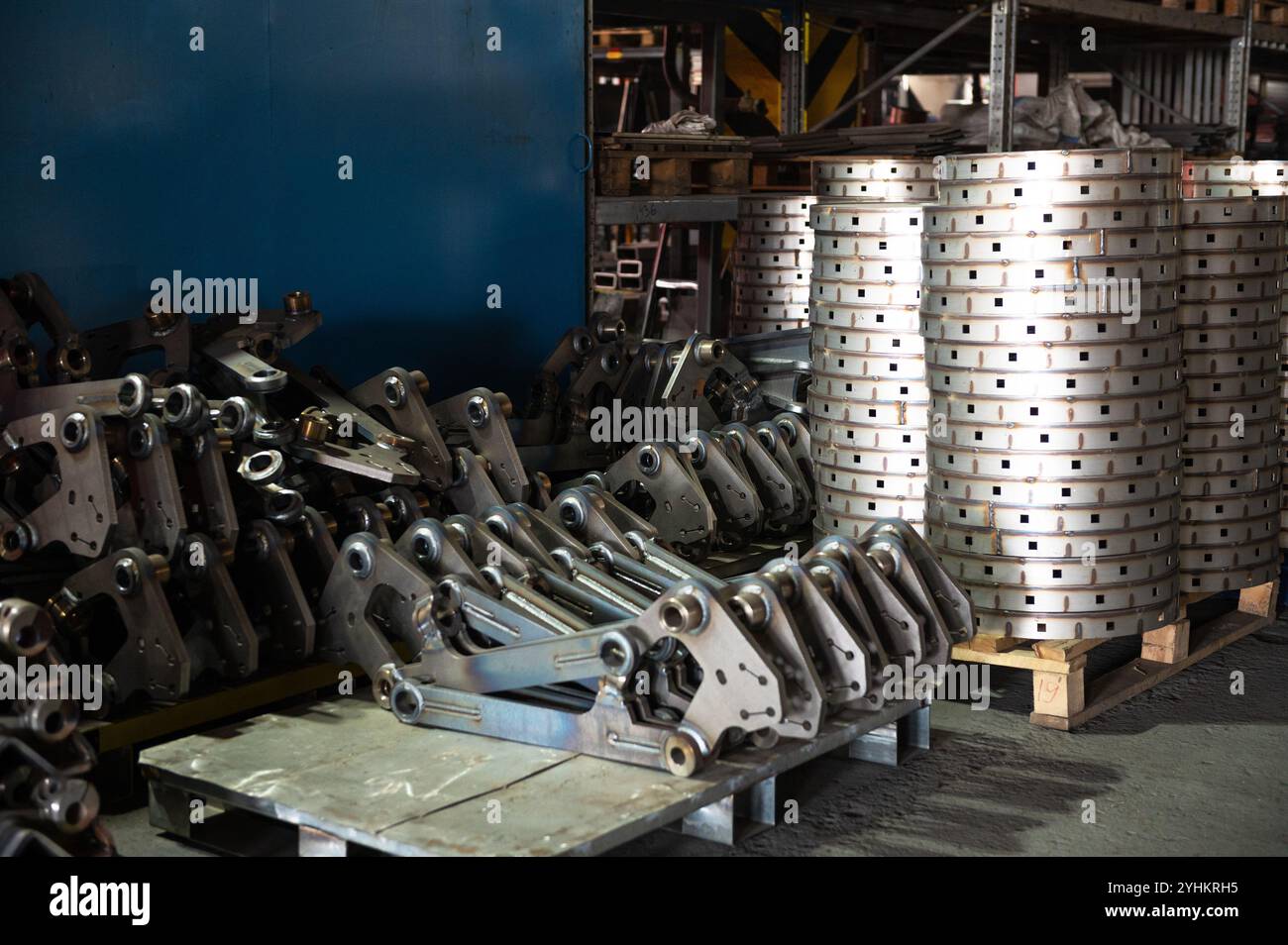A factory storage area filled with stacks of industrial metal parts and ...