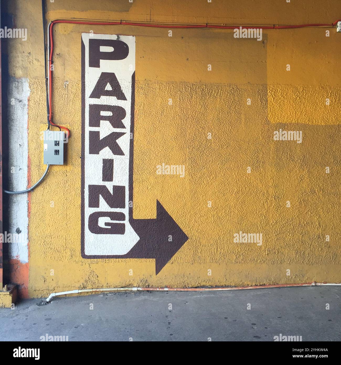 Vintage parking sign painted on a yellow textured wall, pointing right ...
