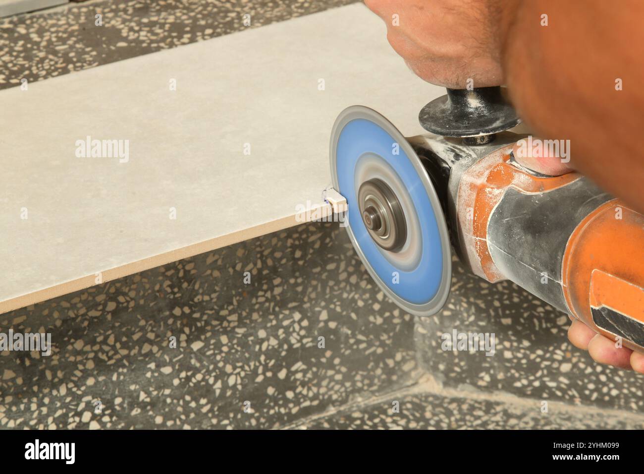 Worker cutting ceramic tile with disc grinder machine. DIY home ...