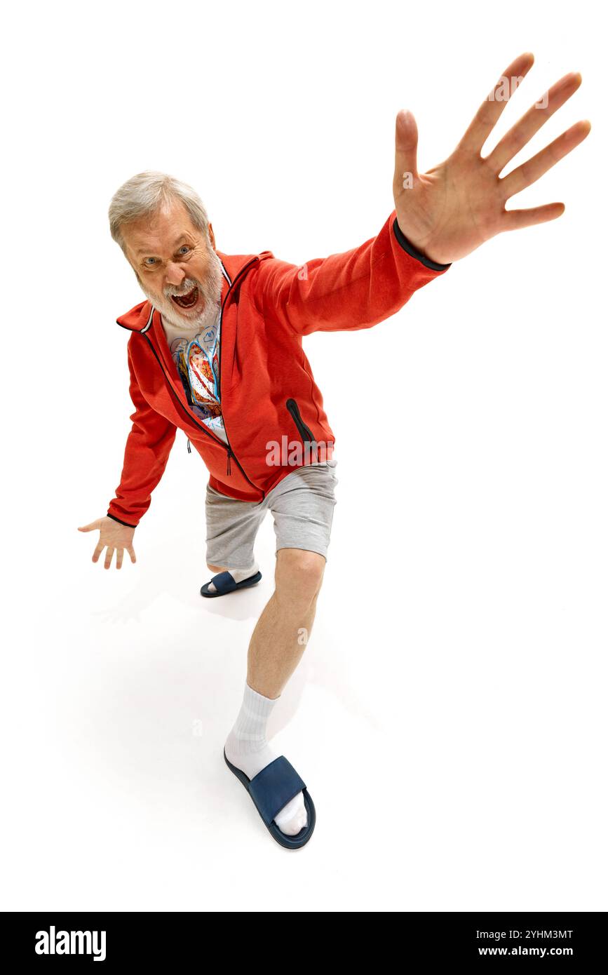 Senior man dressed red jacket, shorts and slippers dancing with joy ...