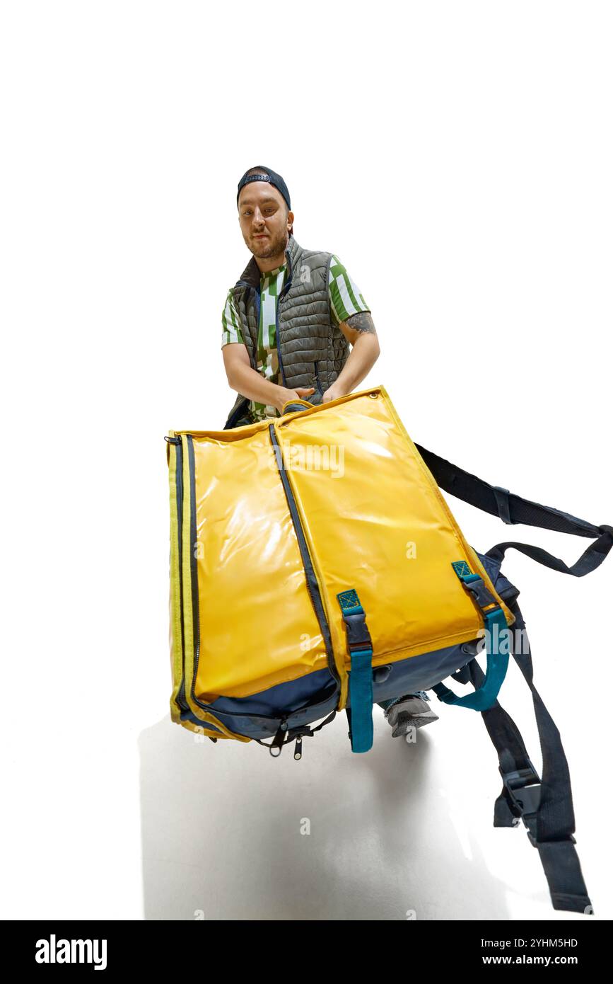 Wide angle photo of young man, courier, dressed casually and carrying ...