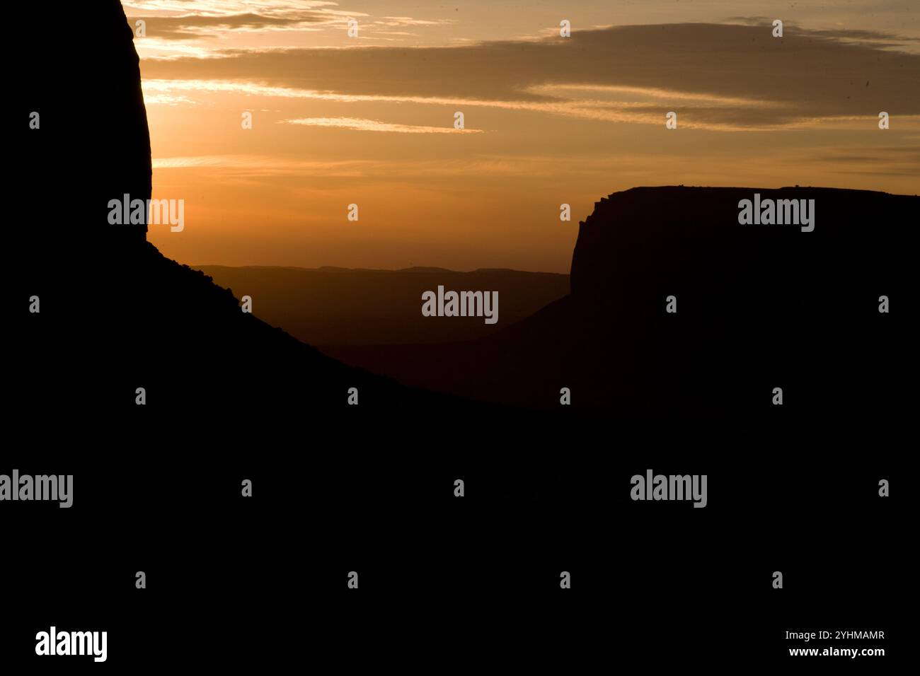 Sunrise paints the clouds above Monument Valley in warm colors in ...