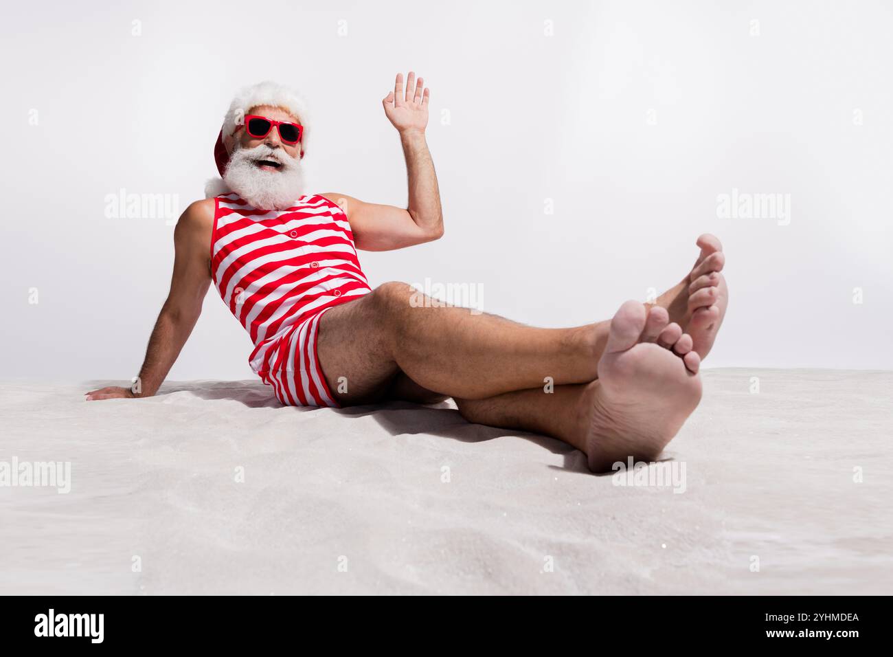 Photo of optimistic santa claus relax rest after winter holidays isolated on white sandy beach ...