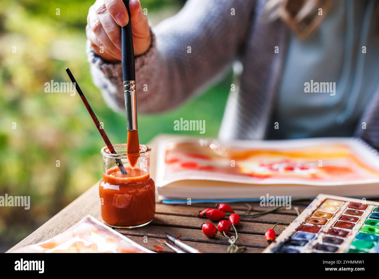 Watercolor painting. Woman artist is cleaning paintbrush in water and ...