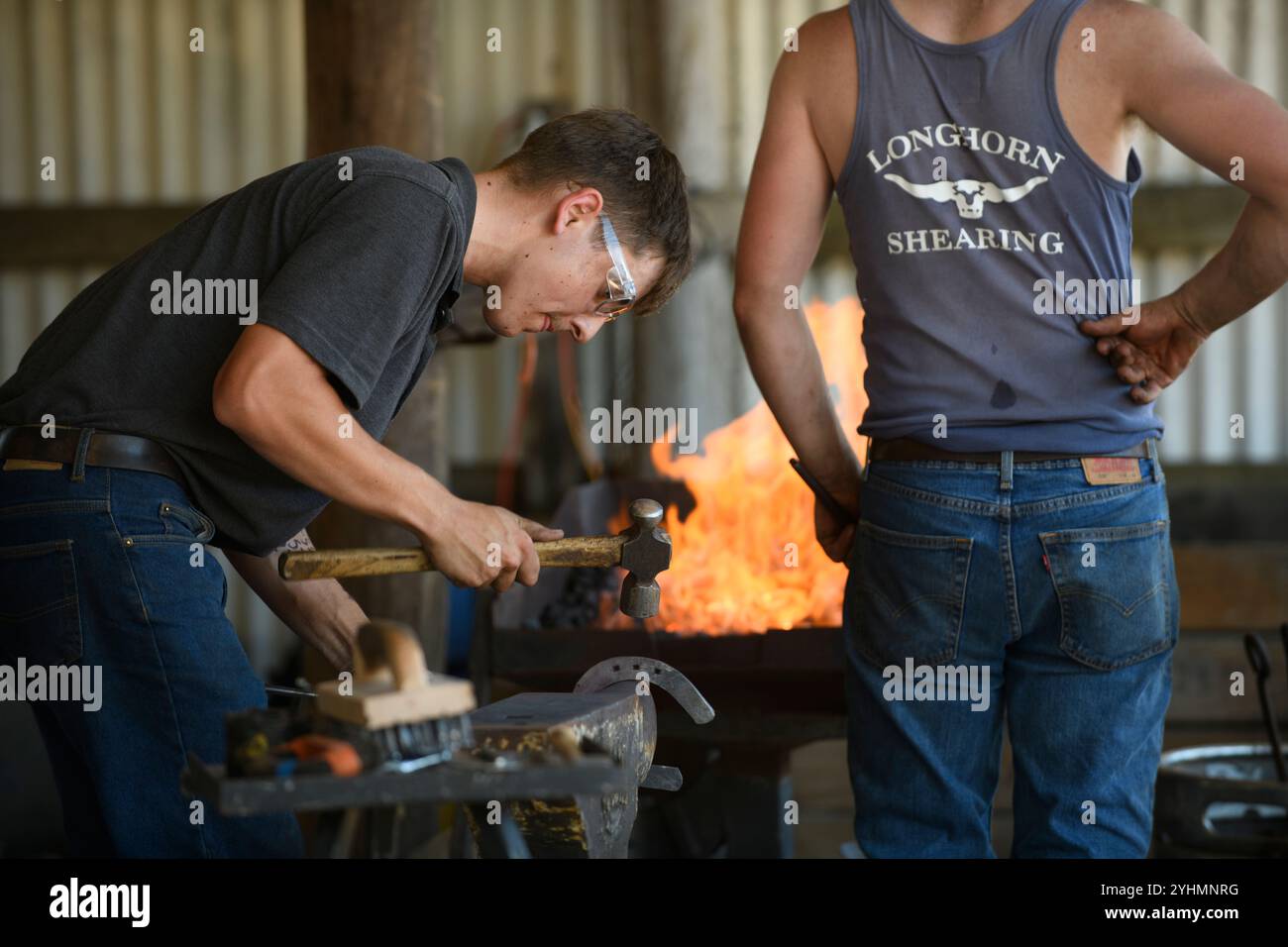 Young blacksmith working on making horseshoe, with forge-fire in background Stock Photo - Alamy