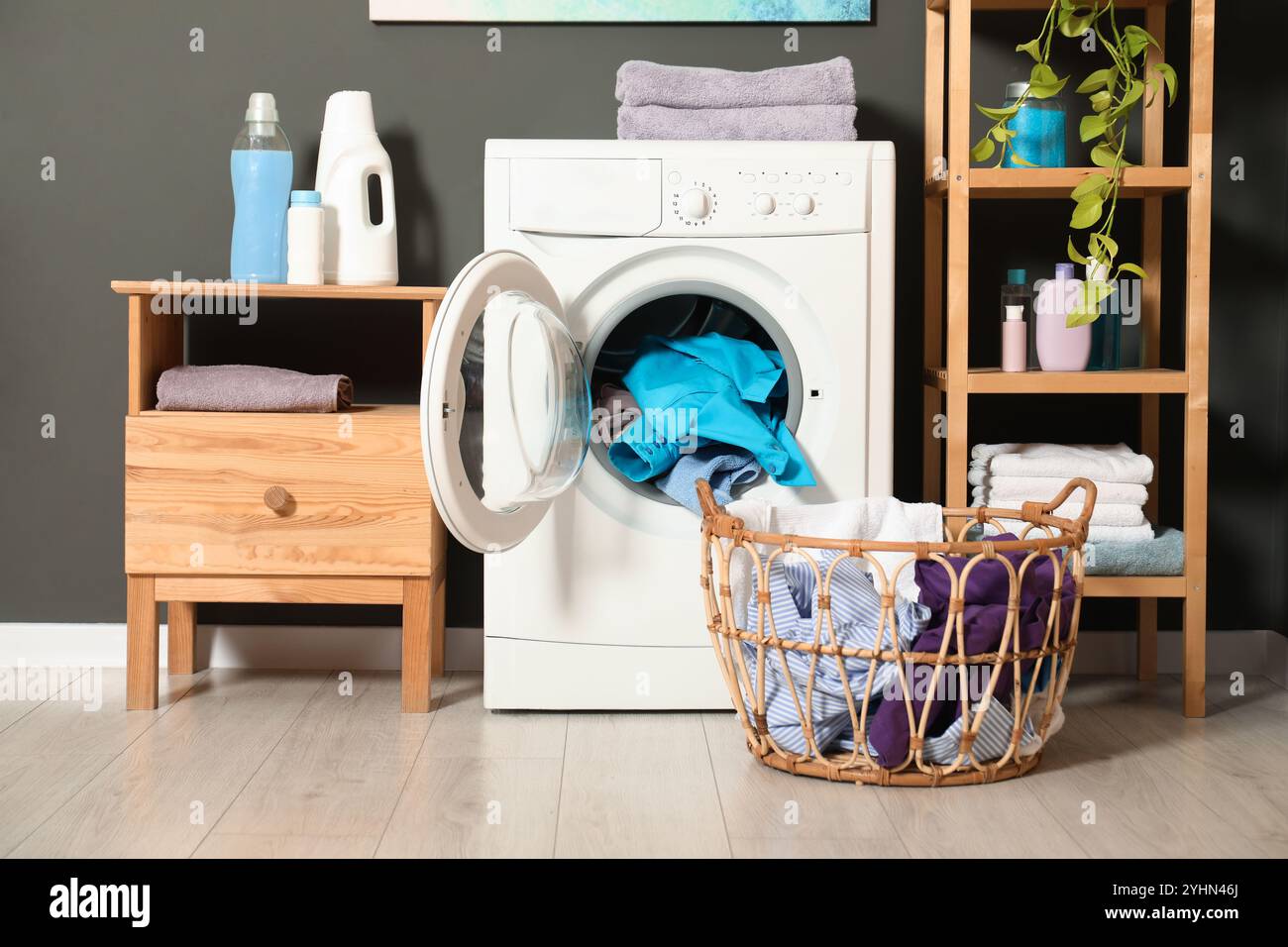 Washing machine, detergents and basket with laundry in room Stock Photo ...