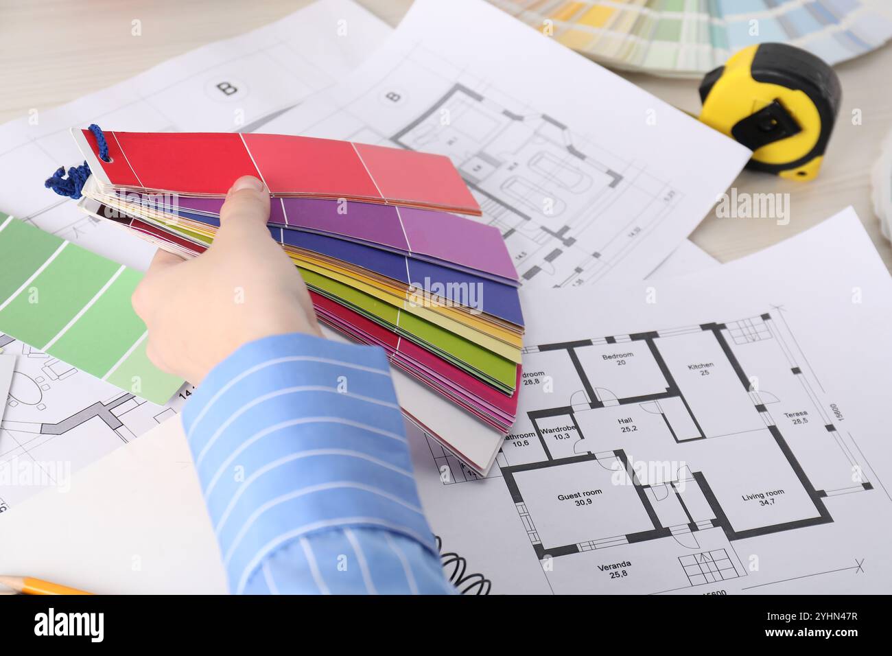 Designer with color selection chart working on house project at table ...