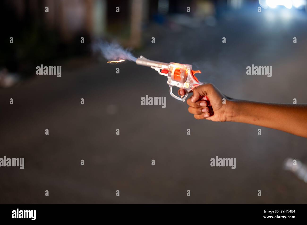 A hand fires a toy cap gun, sparks flying in the night. Childhood, play ...