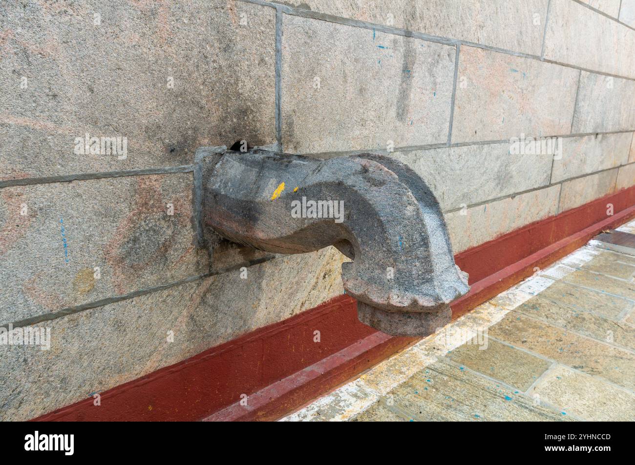 Ancient stone waterspout on a granite wall, showcasing traditional ...