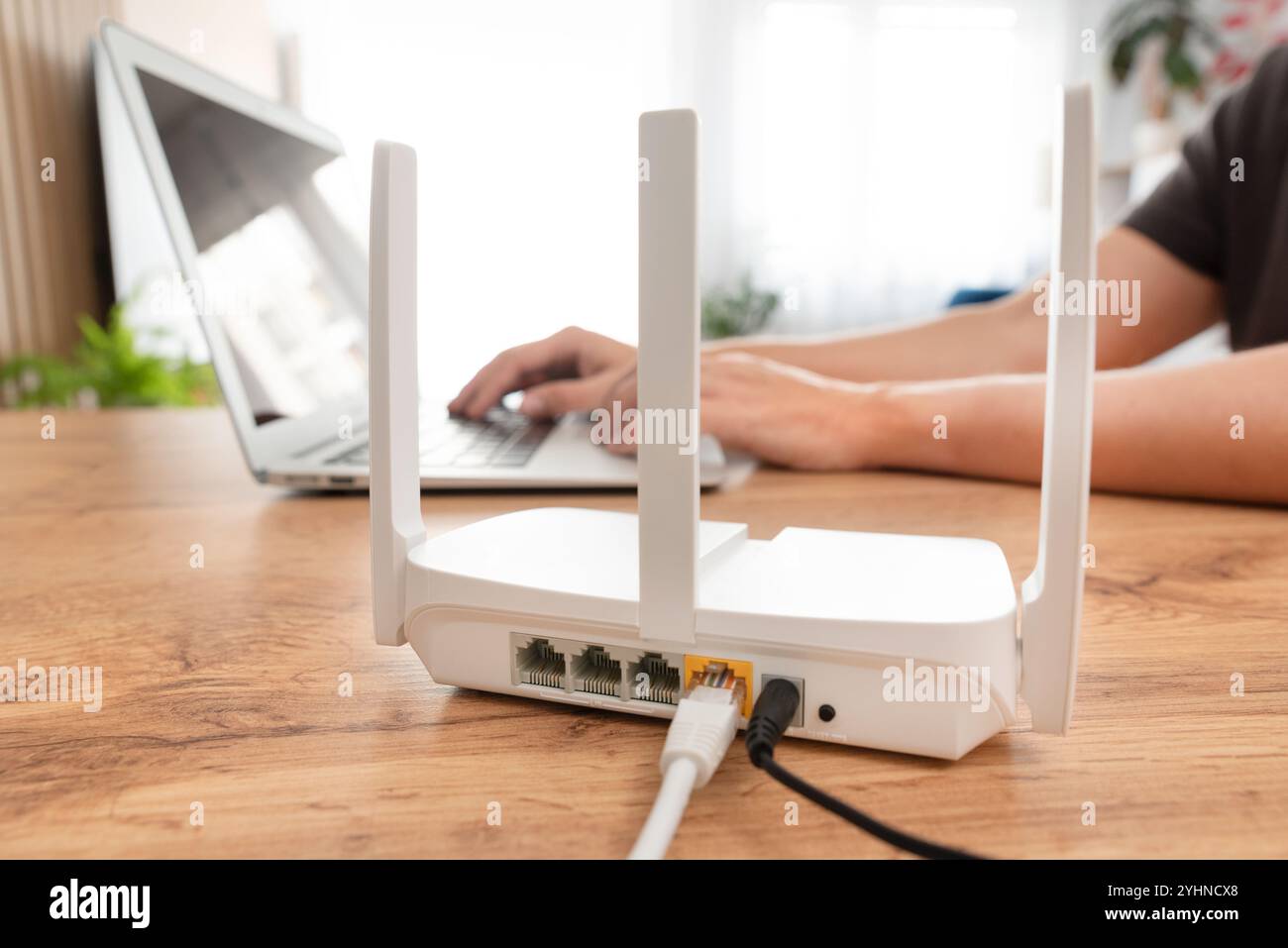 Person connecting modern wi-fi router on light table in living room ...