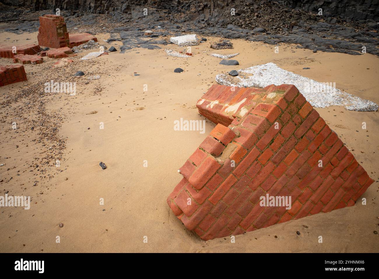 Brick buildings fallen onto a beach due to coastal erosion Stock Photo ...