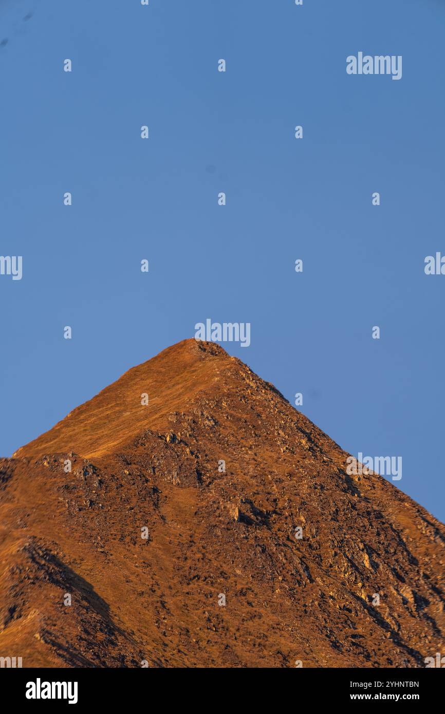 mountain peak with ridge in red brown colors against blue sky, copy ...