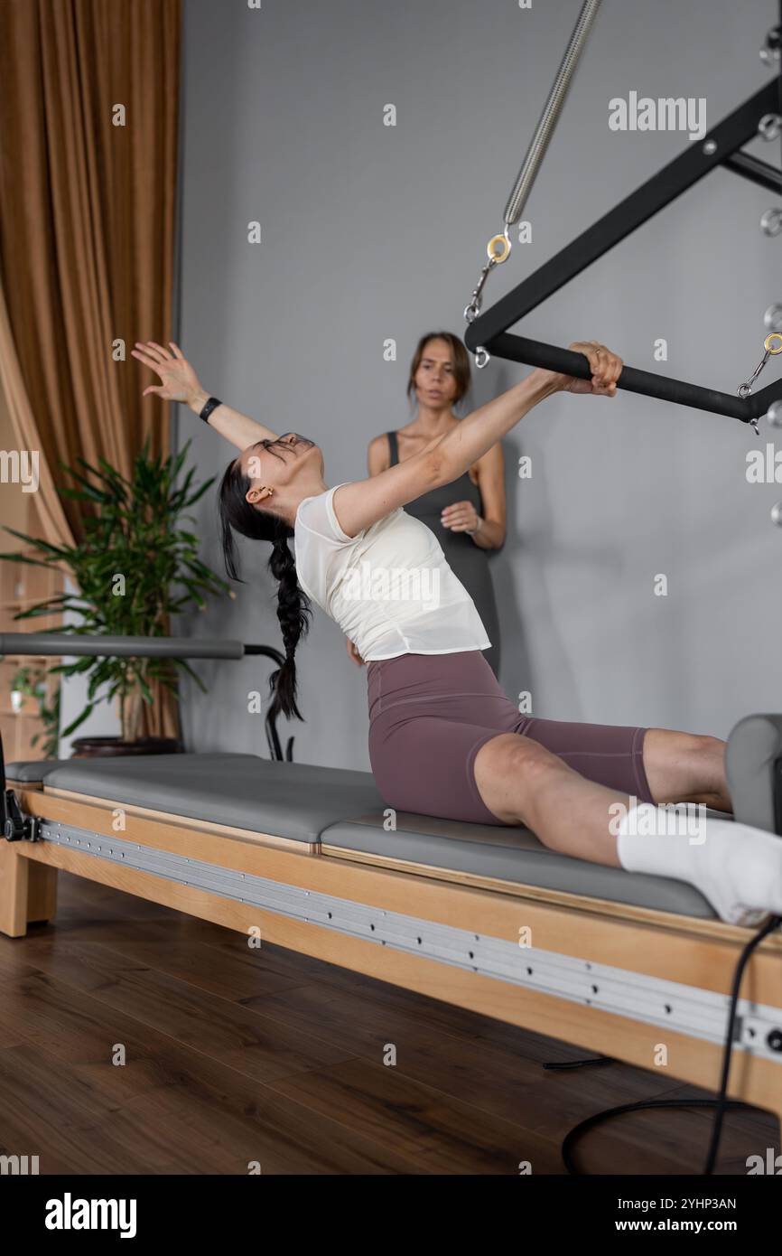 A Pilates Instructor helps a client with stretching exercises on ...