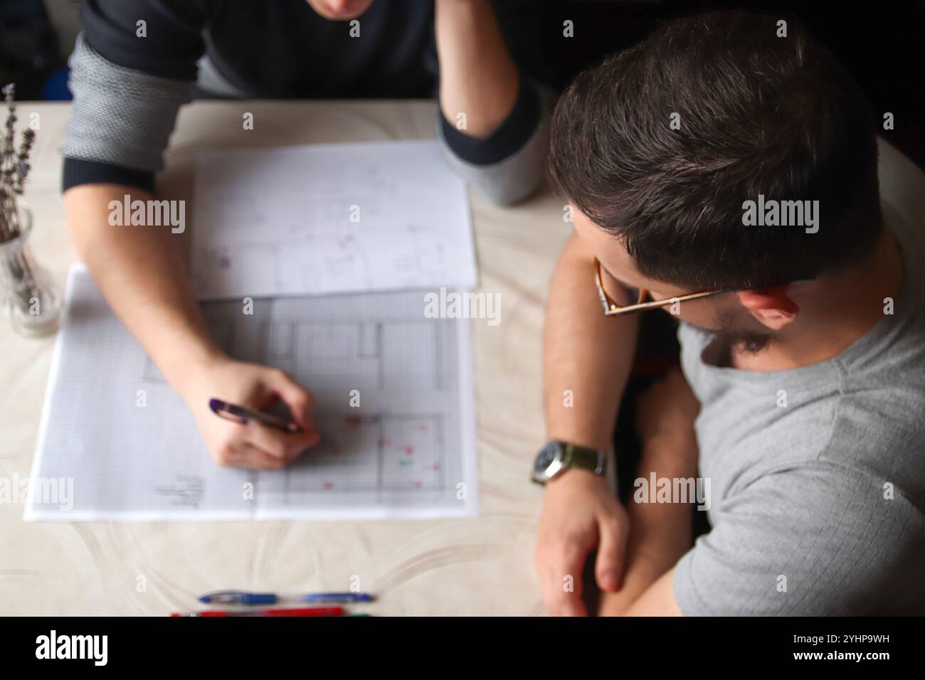 An overhead view of architects' hands working on detailed building ...