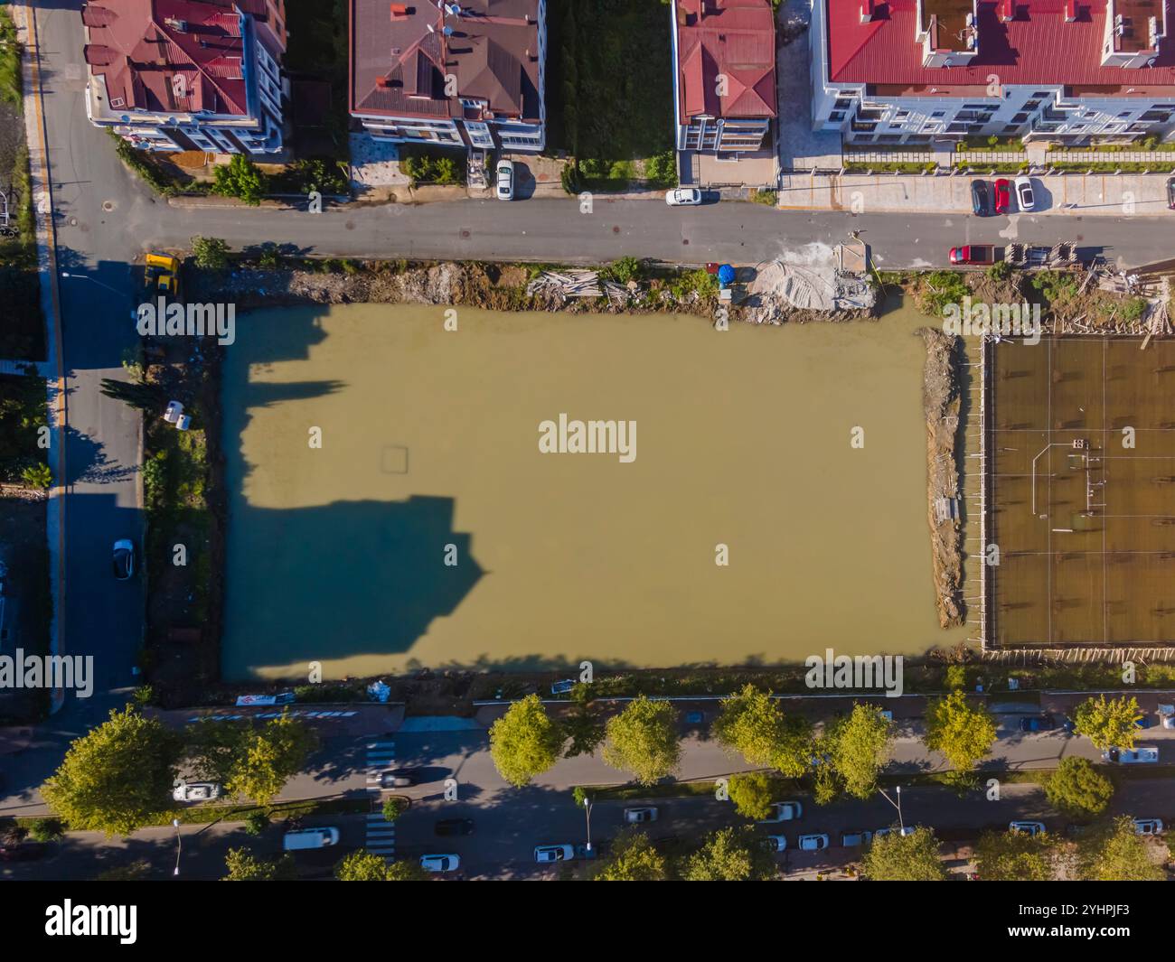 A city street with a large green field in the middle. The field is ...