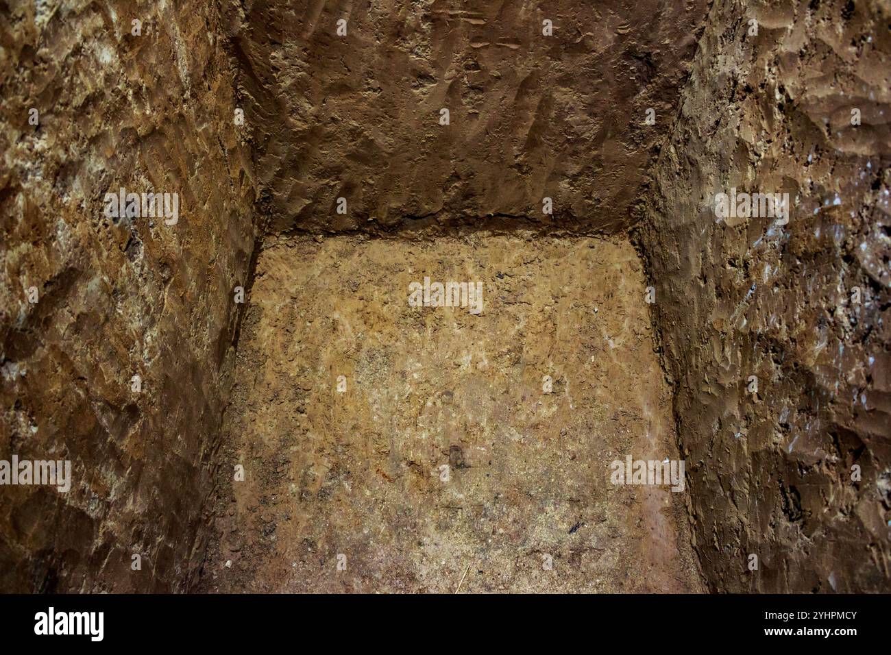 Hand dug deep rectangular hole in the ground, view of grave pit from ...