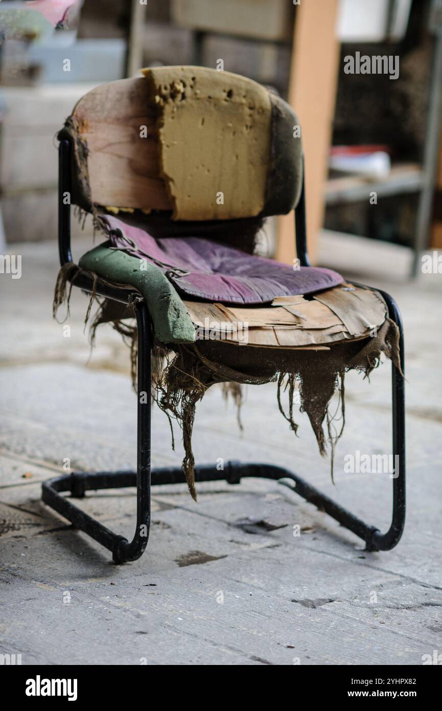Torn and tattered old, metal frame chair with ripped fragments of ...