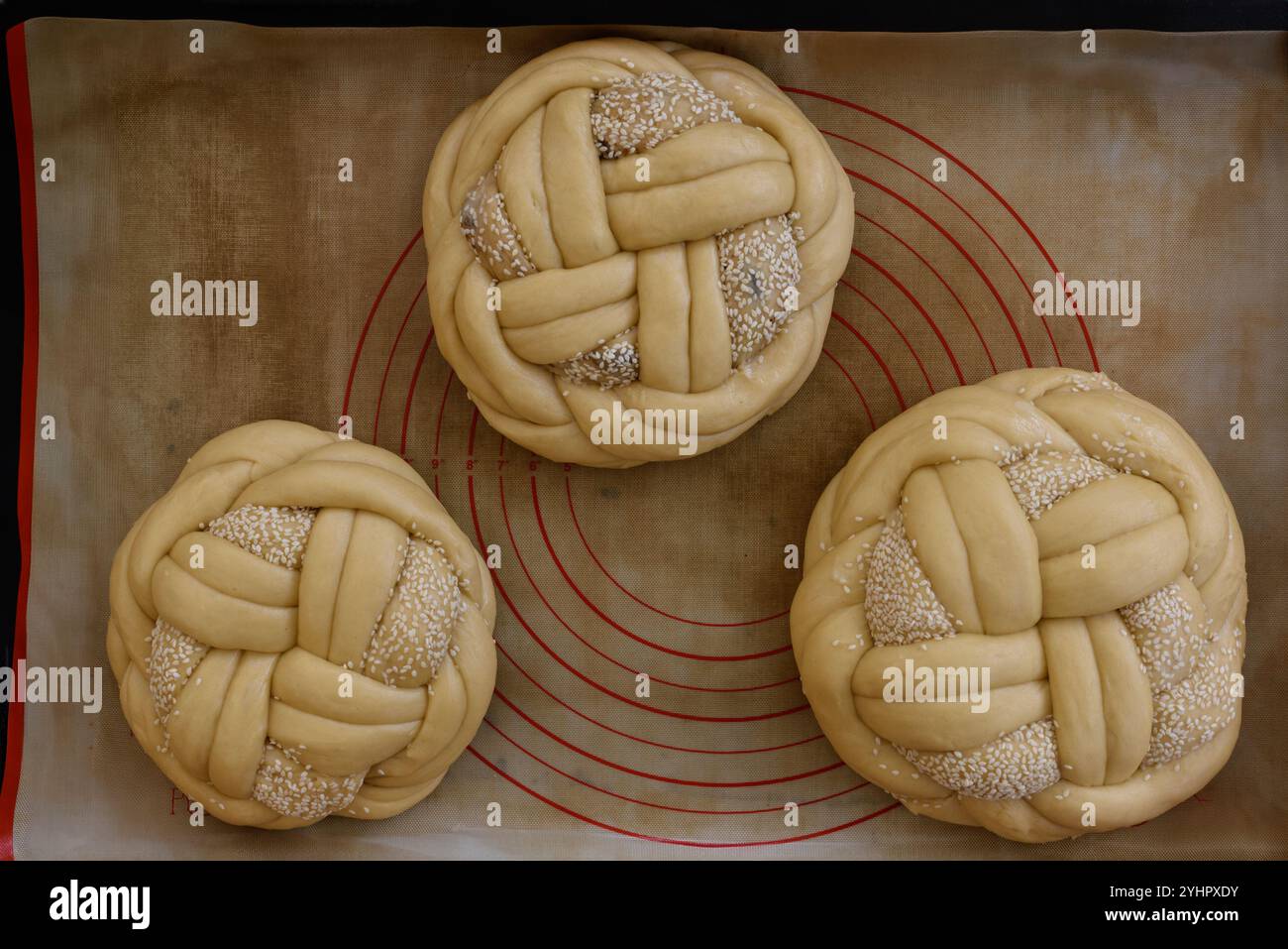 Unbaked, round, braided Jewish holiday challah loaves topped with ...