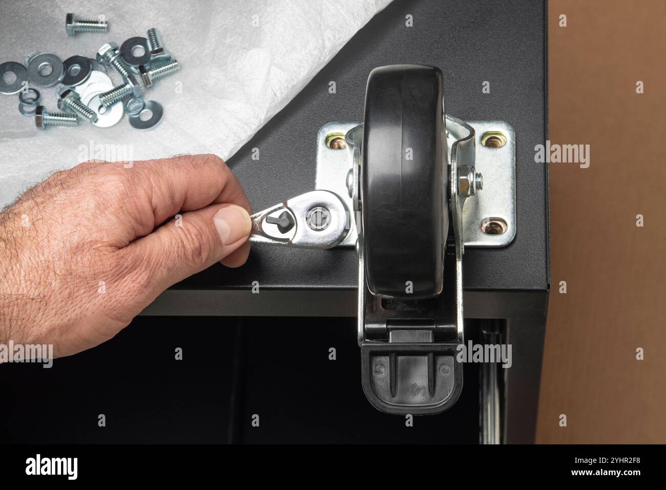 Hand installing a caster on a new tool chest Stock Photo - Alamy