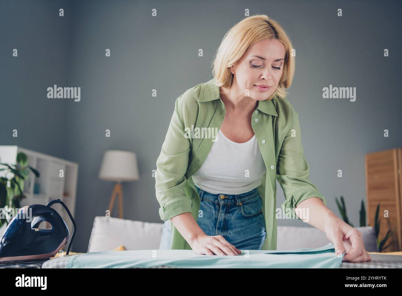 Middle-aged woman with blond hair at home, performing housework ...