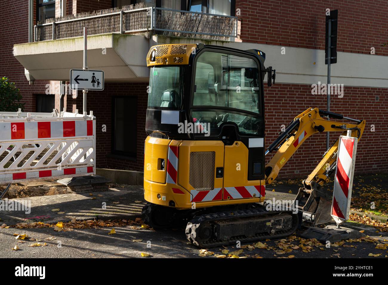 A compact excavator parked near a construction site in an urban area ...