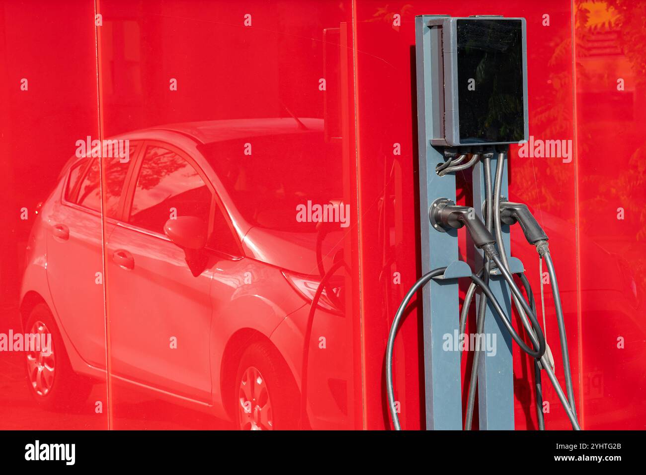 A bright red backdrop features an electric vehicle charging station ...