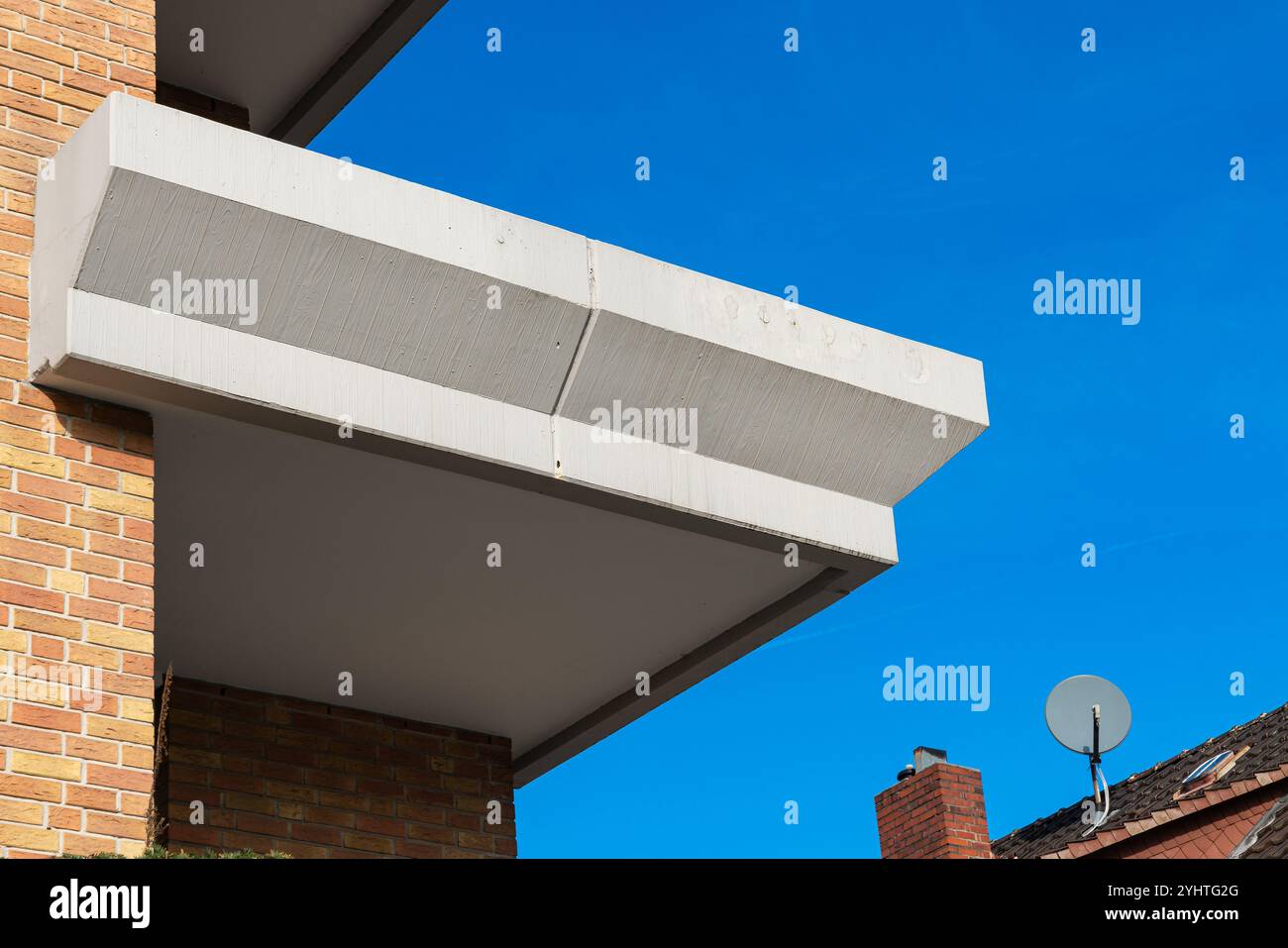 A concrete balcony protrudes from a brick building, presenting a ...