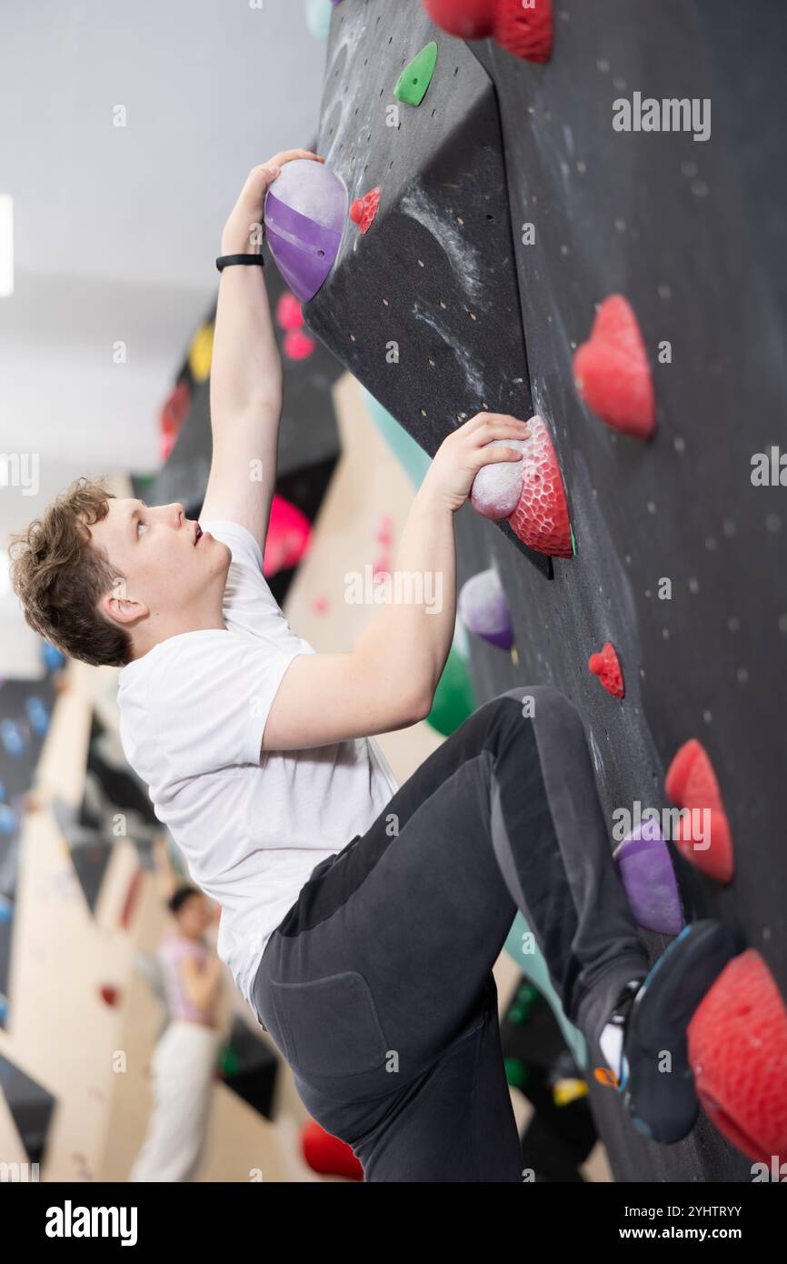 Teen guy practicing rock climbing on climbing wall Stock Photo - Alamy