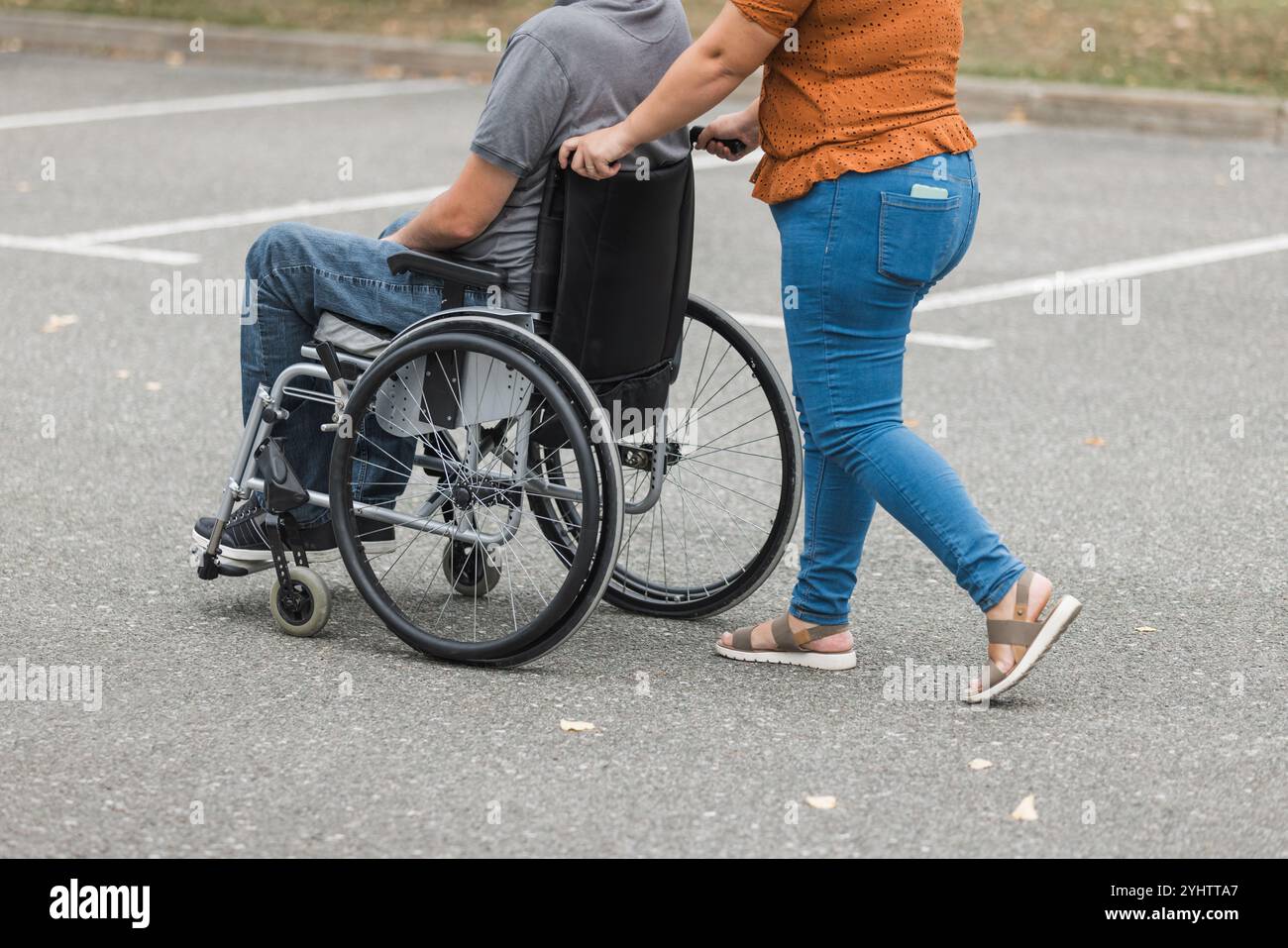 Personal assistant helping a man with disability to push a wheelchair ...