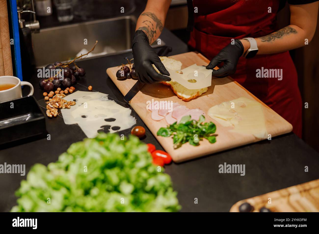 A chef is making a delicious sandwich with fresh ingredients to create ...
