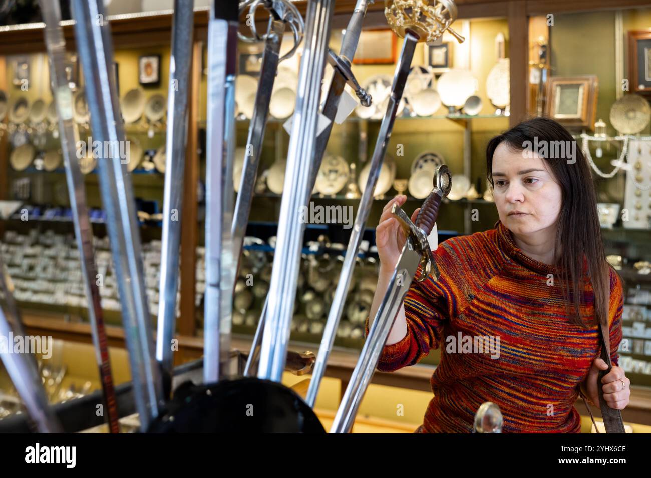 Female traveler viewing at handmade forged swords in gift shop of ...