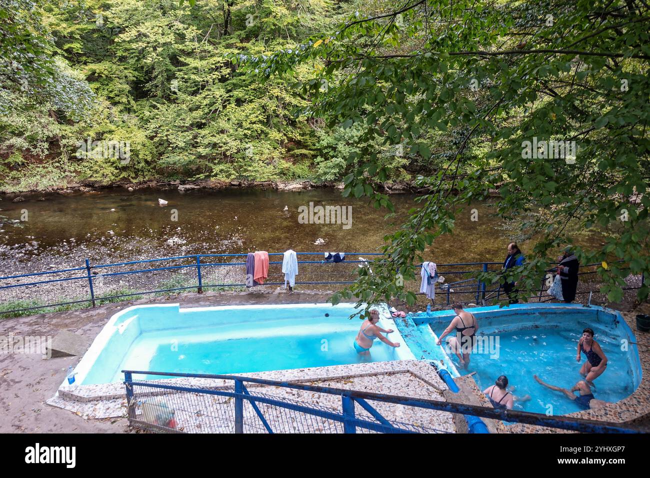 A serene outdoor pool area with people enjoying a dip in the hot ...