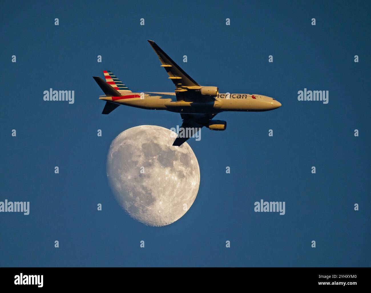 An American Airlines Boeing 777 passes a three-quarter moon at sunset ...
