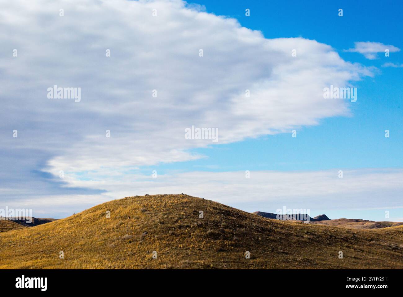 Small hills and badlands rising above the grasslands and plains below a ...