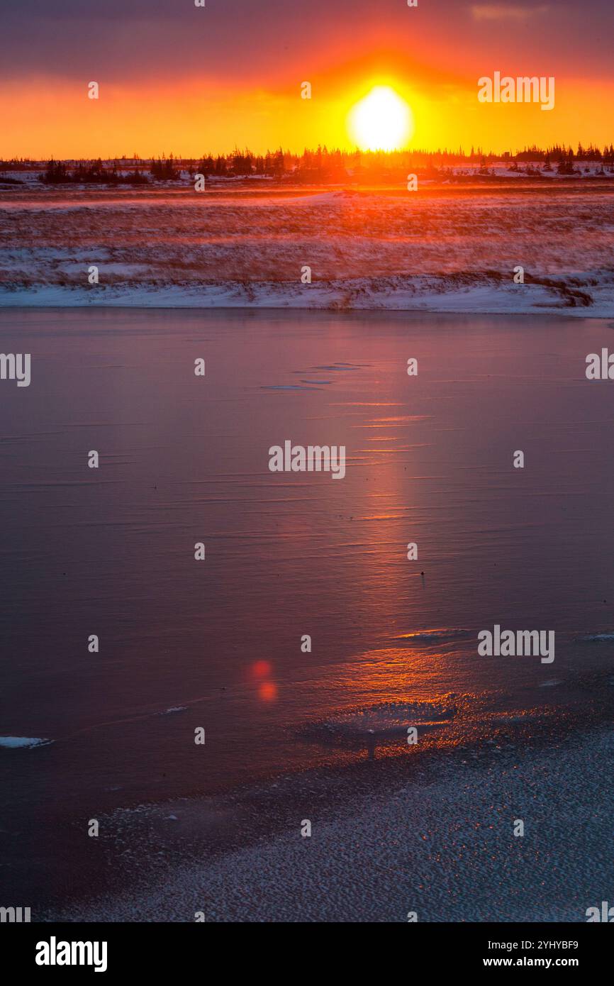 The sun sets over a frozen landscape in Churchill, Manitoba, Canada ...