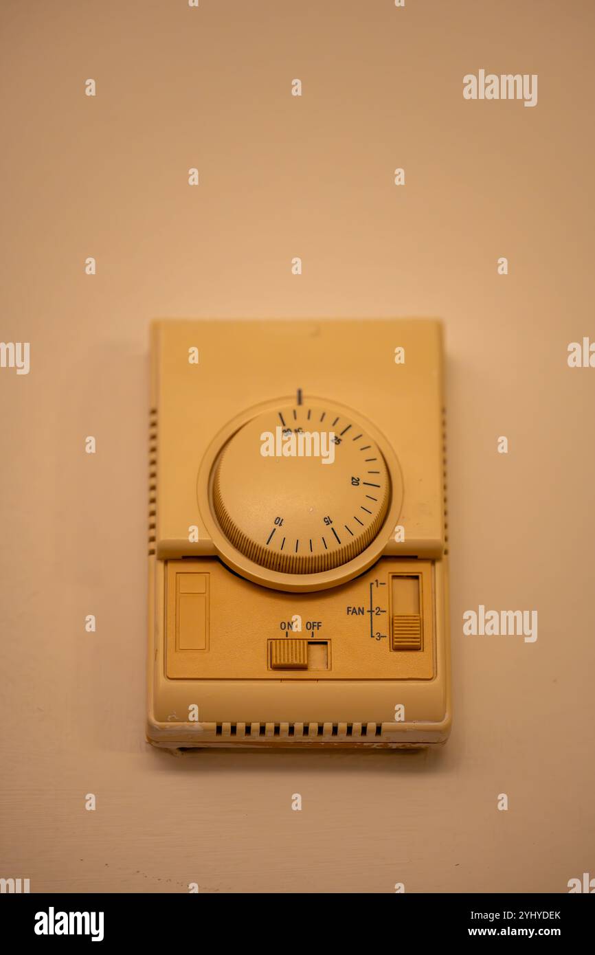 This close-up image features a vintage mechanical thermostat, a classic ...
