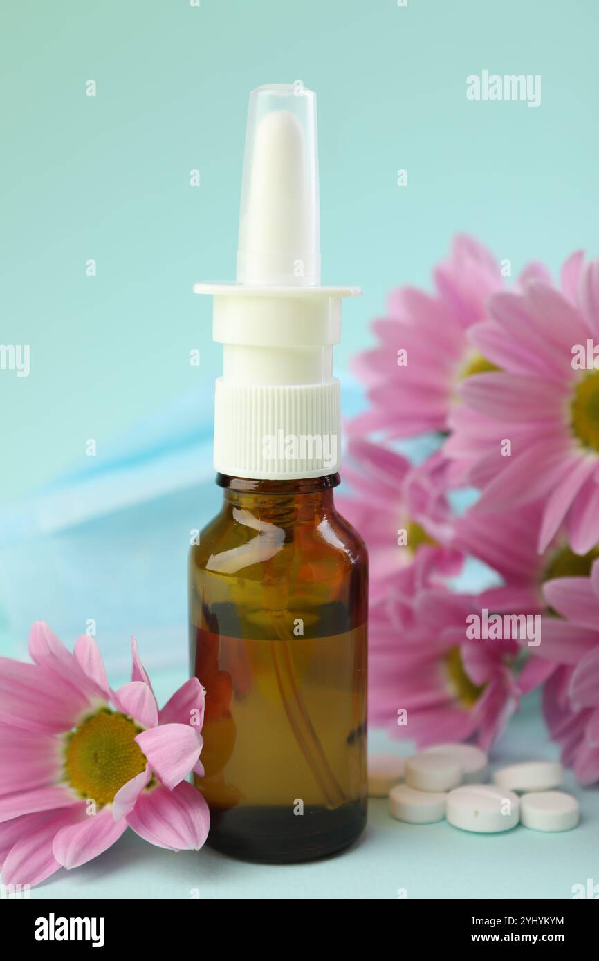 Allergy treatment. Nasal spray, pills and flowers on light blue ...