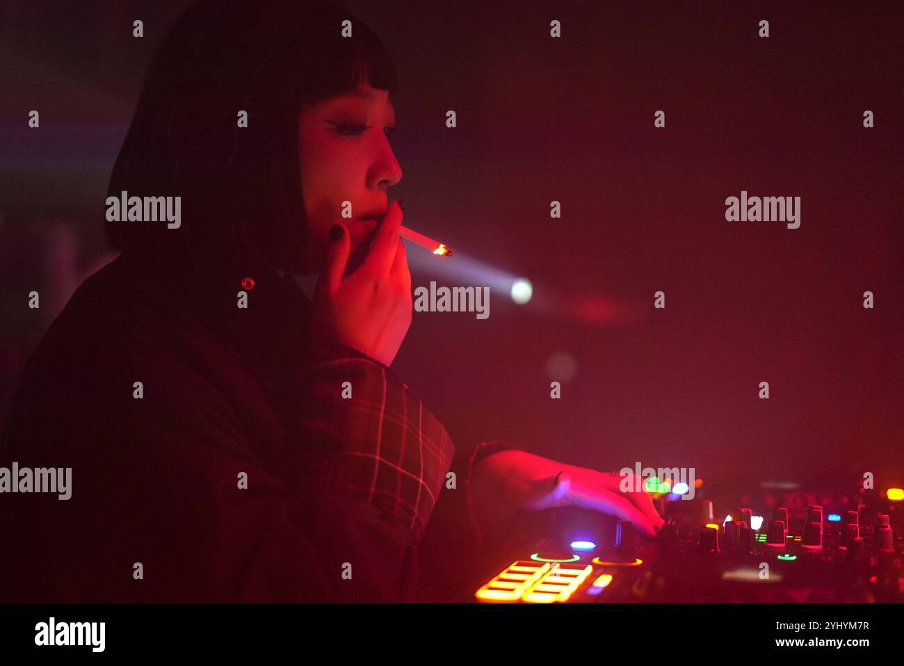 A DJ who goes by the stage name "Kuro" smokes a cigarette as she plays ...