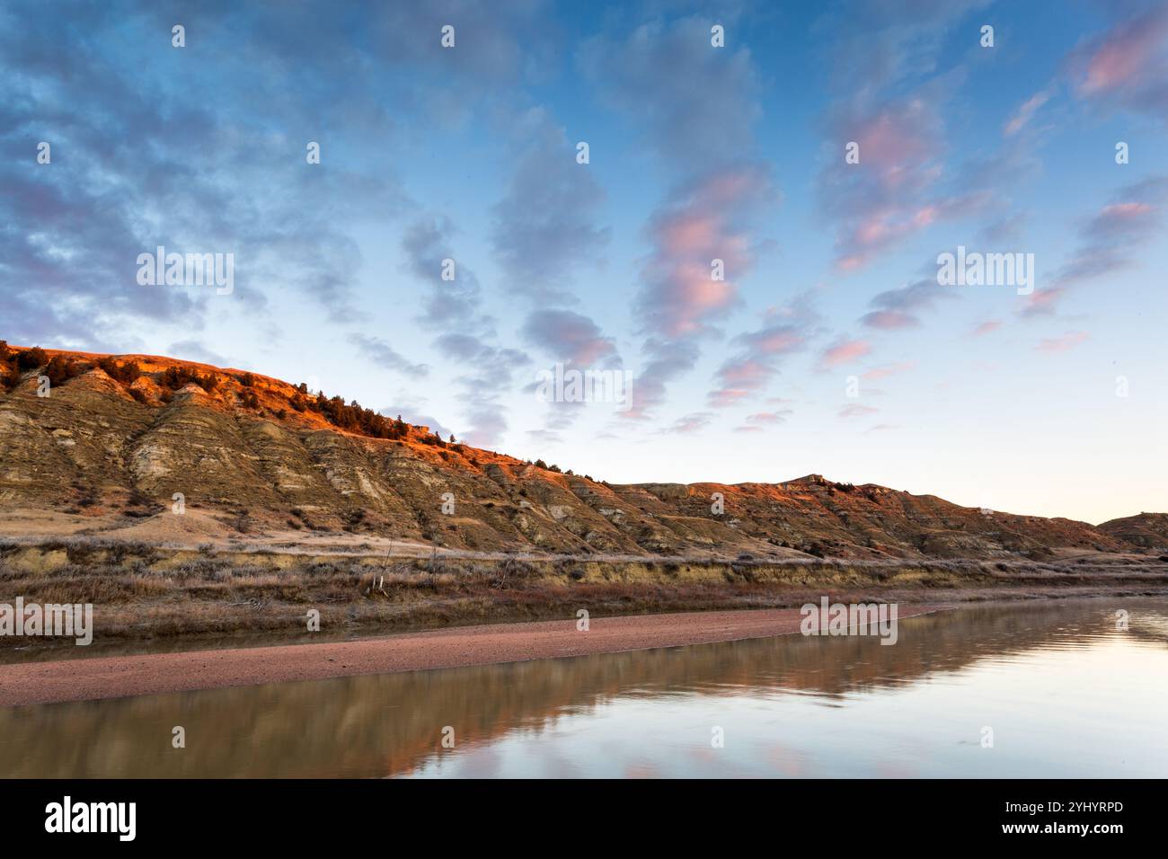 The Little Missouri River flowing below badlands hills and sunrise ...