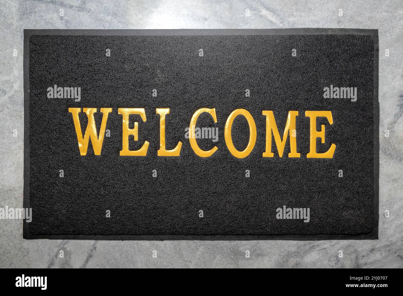 Top view of black doormat with welcome text on it with floor background ...