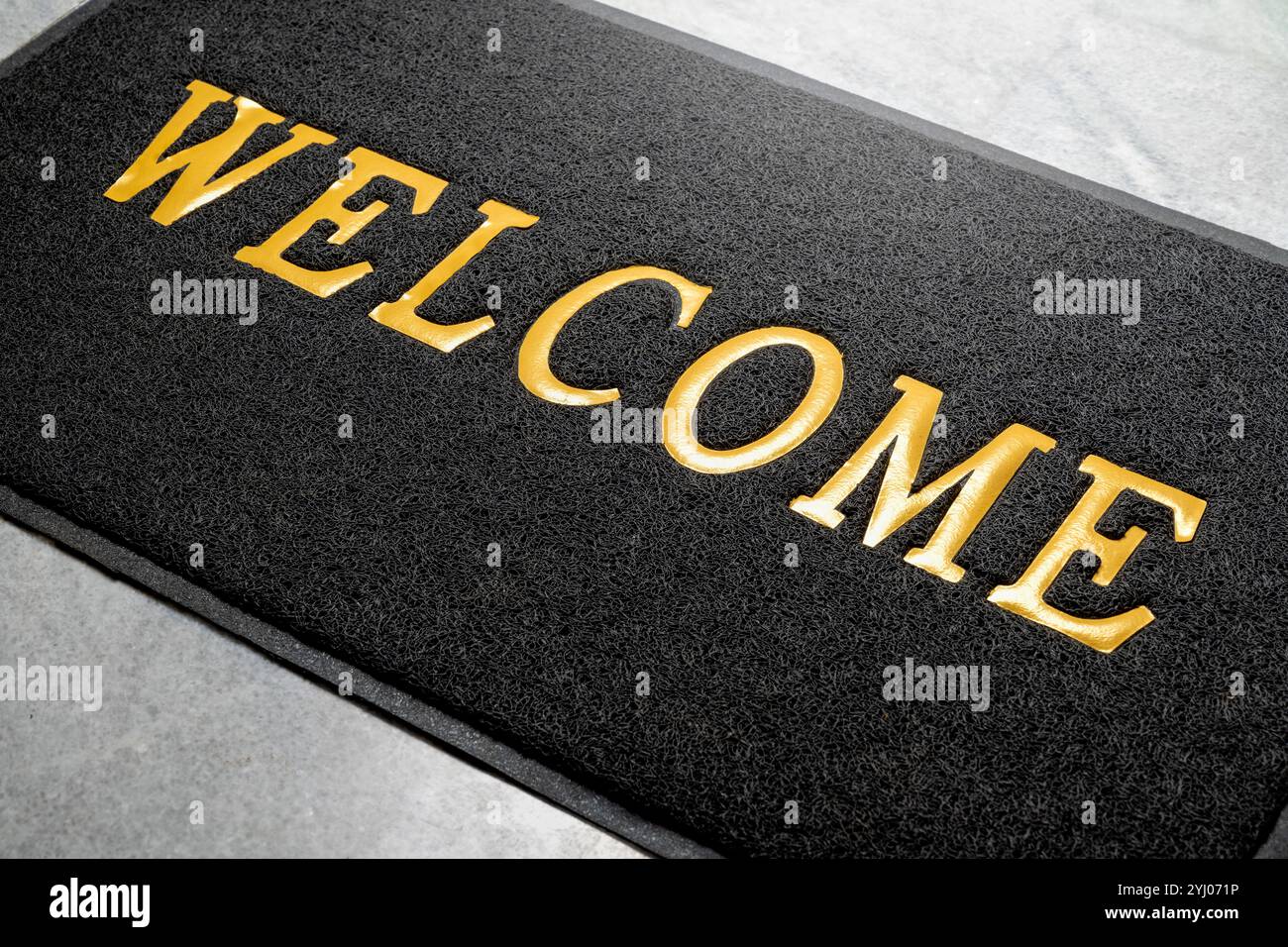 Black doormat with welcome text on it with floor background. Welcome ...