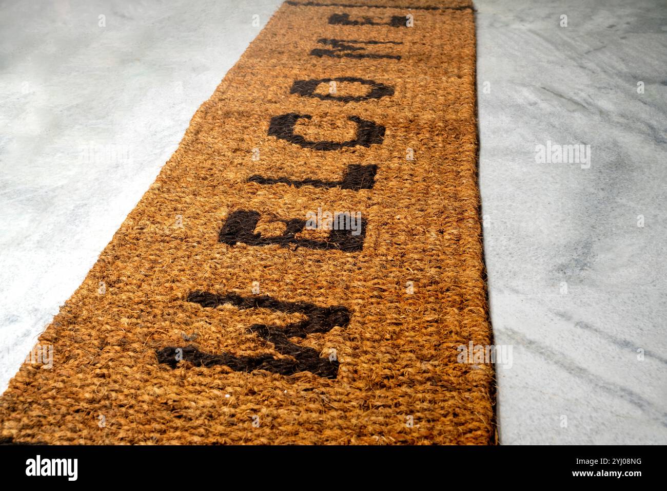Brown doormat with welcome text on it with floor background. Welcome ...