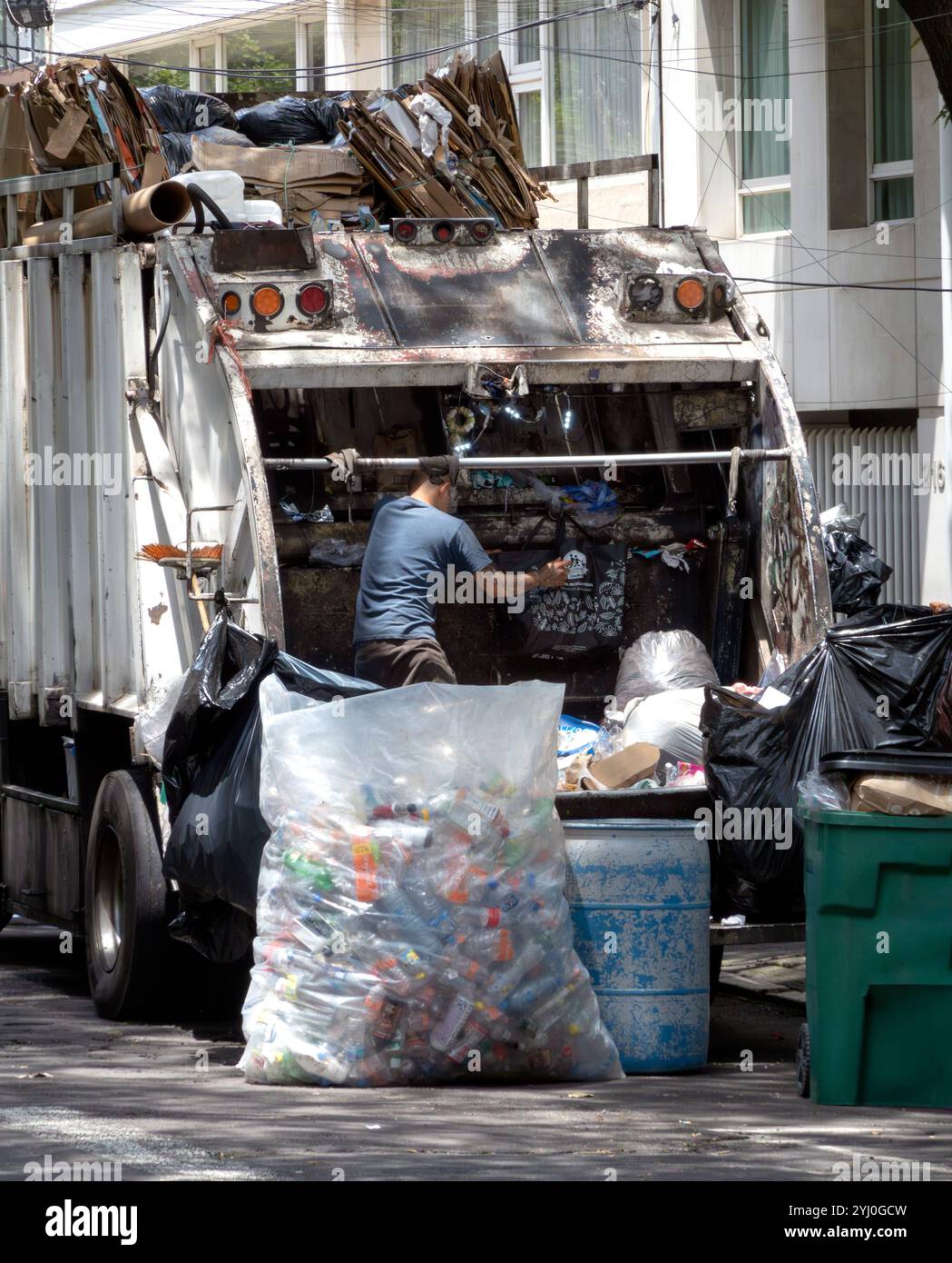 Man in a compacting trash truck sorting trash in Mexico City, Mexico ...
